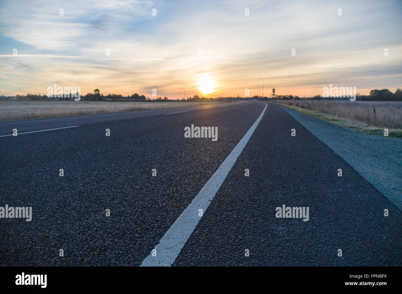 Empty turning asphalt road closeup and sunrise cloudscape on backdrop ...