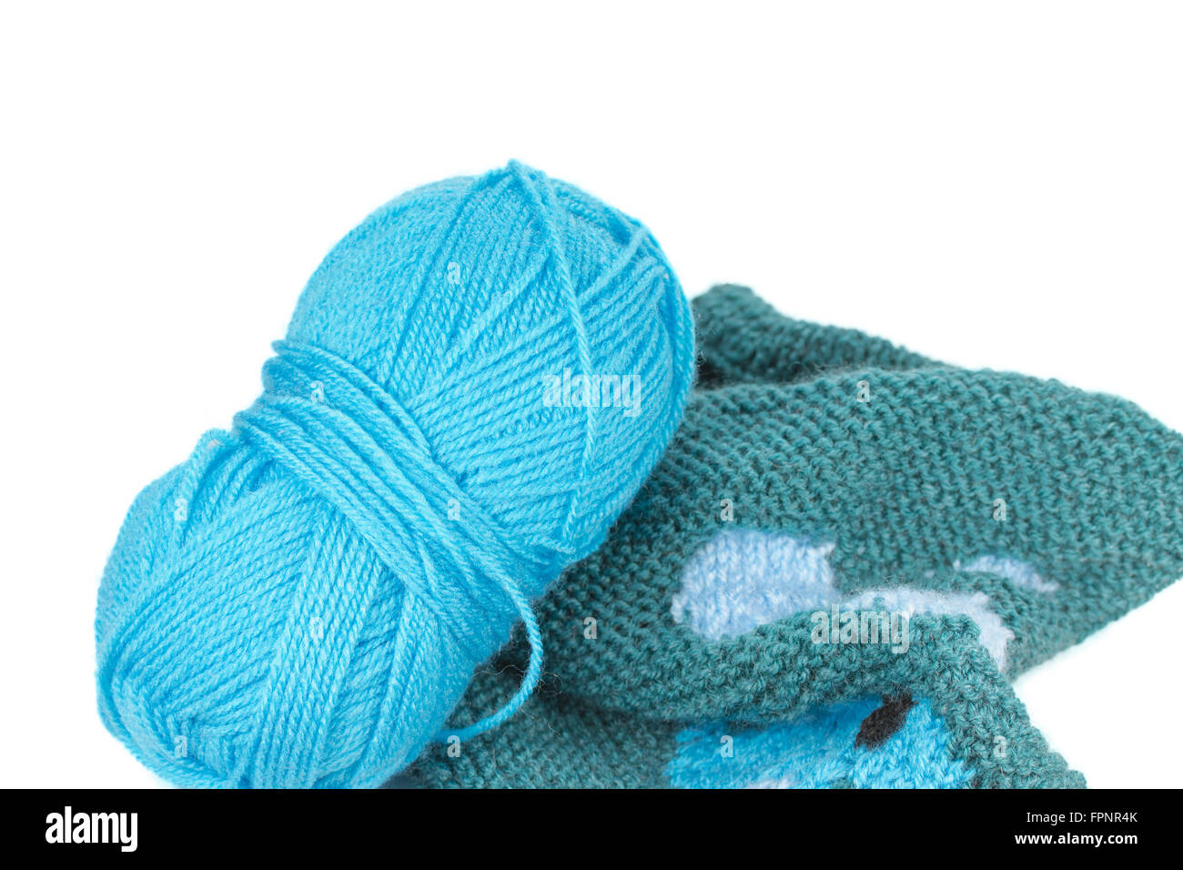 Blue knitting yarn and knitted piece of patterned sweater isolated on ...