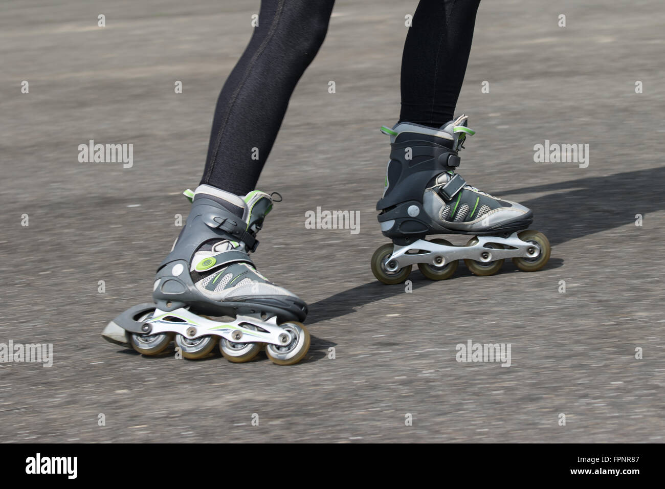 Dynamic closeup view of in-line skates driving along the asphalt road ...