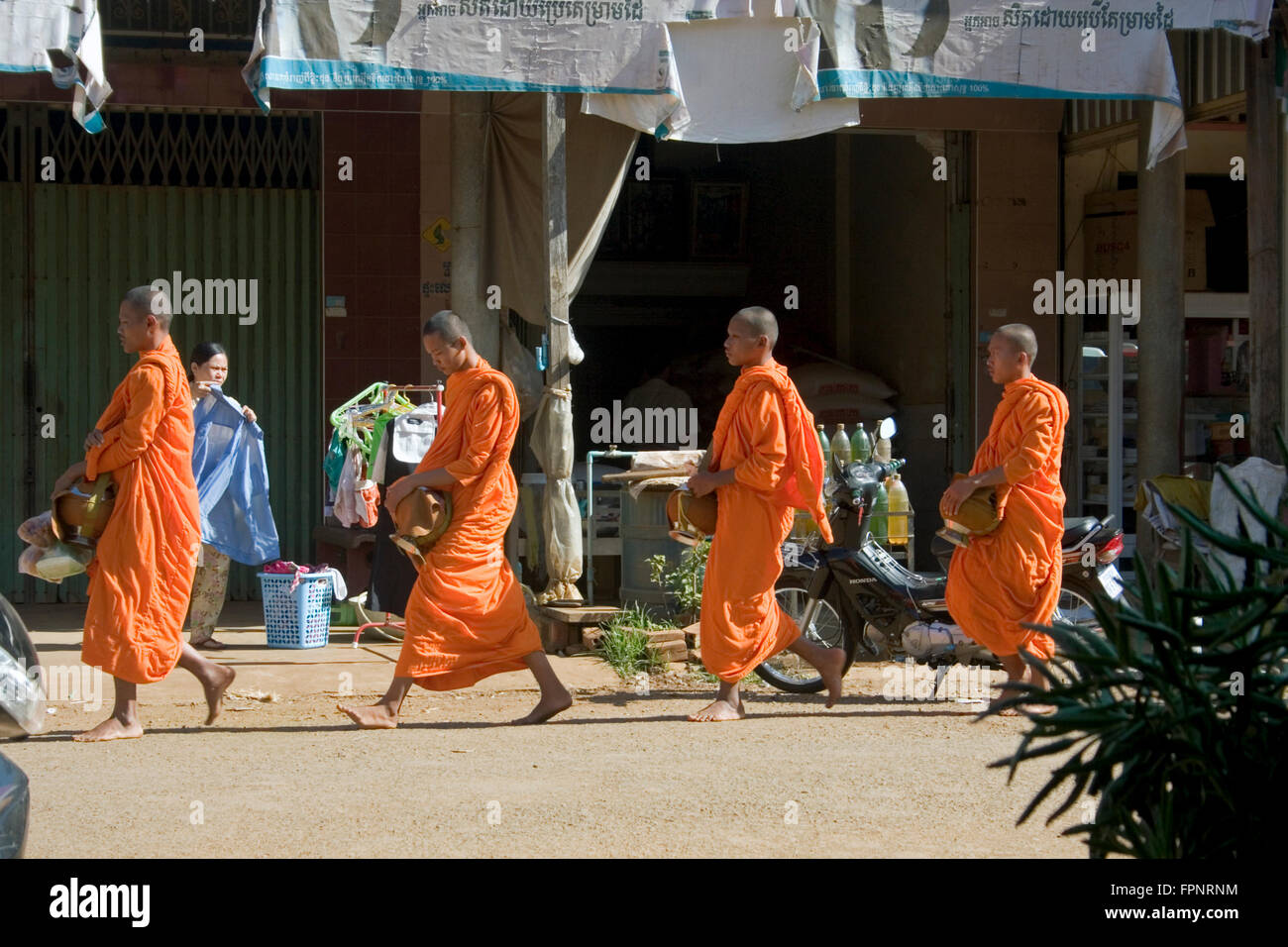 Buddhist monks walk with bare feet collecting alms on a street in Ou ...