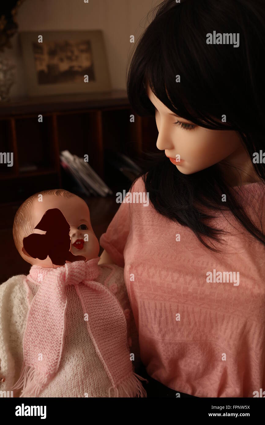 Silicone doll sitting and holding broken puppet with half a face Stock ...