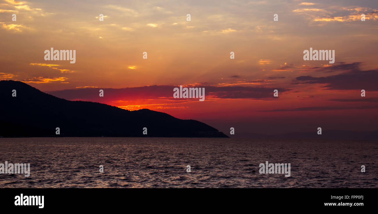Dramatic sunset with red sky. Coastline silhouette in the background ...