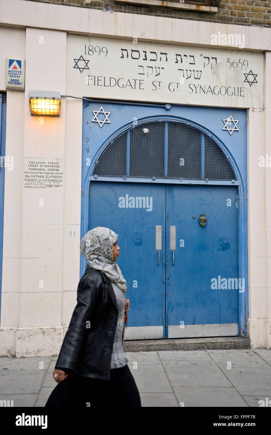 Muslim woman walk past the Jewish Fieldgate St. Grand Synagogue next to ...