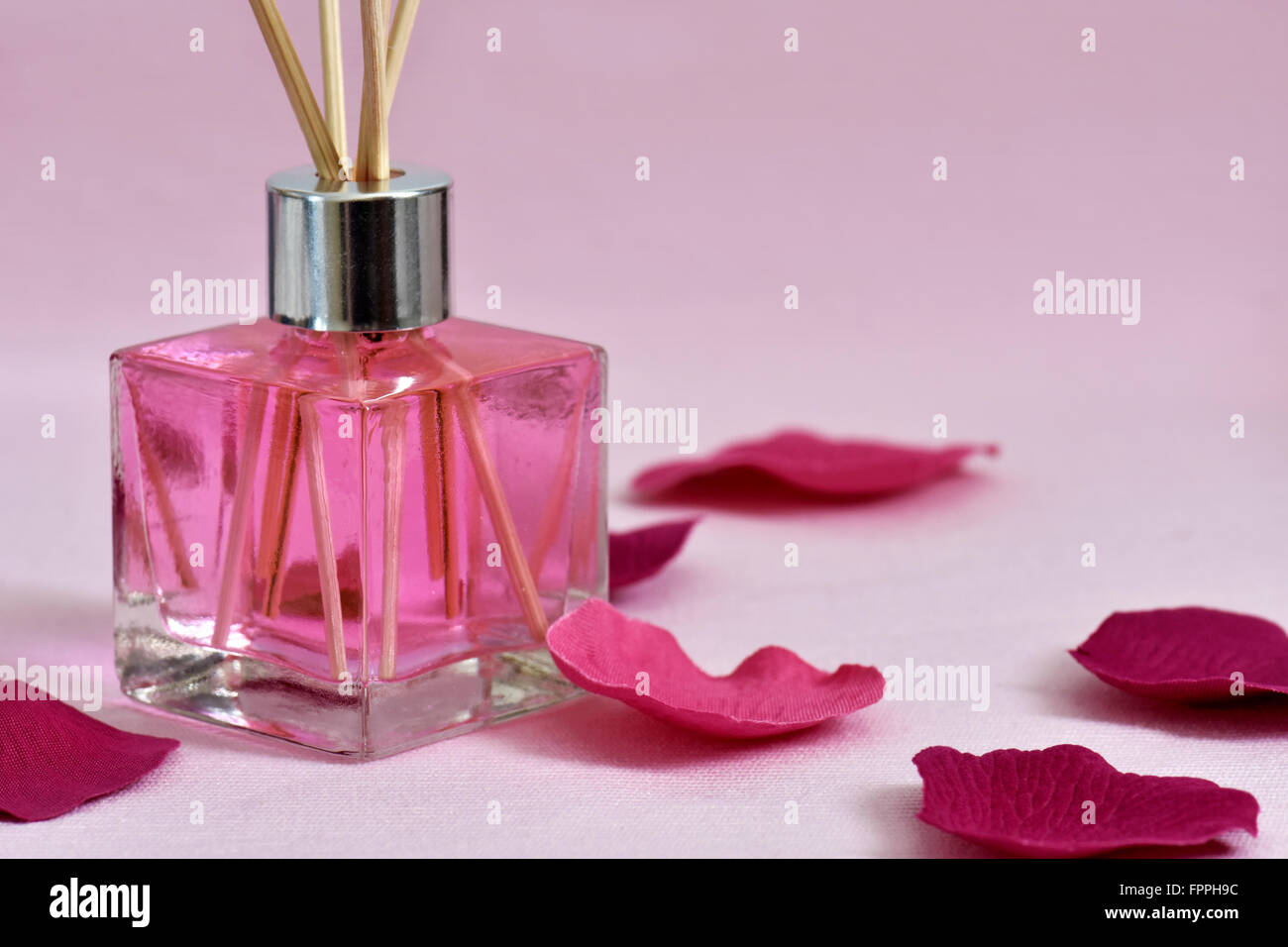 Reed diffuser room scenter on a pink background with fake rose petals ...