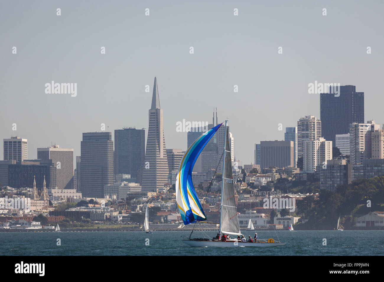 Sailboat with blue and white spinnaker goes past the San Francisco ...
