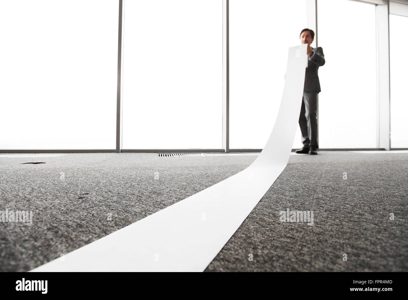 Office worker unrolling long sheet of paper Stock Photo - Alamy
