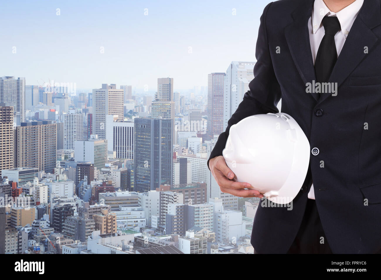 engineer holding white helmet with city background Stock Photo - Alamy