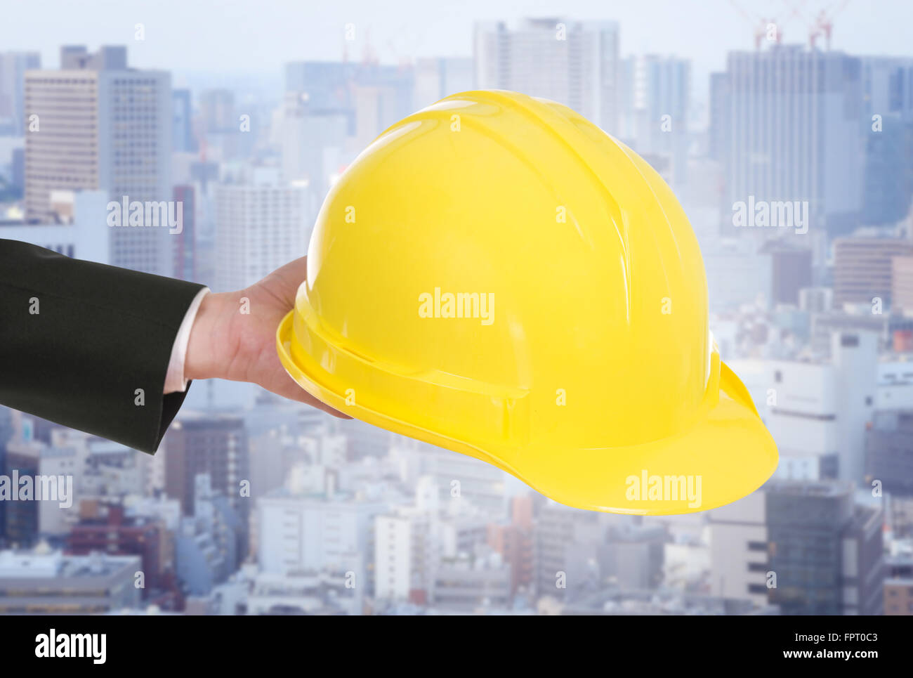 hand of engineer holding yellow helmet with city background Stock Photo ...