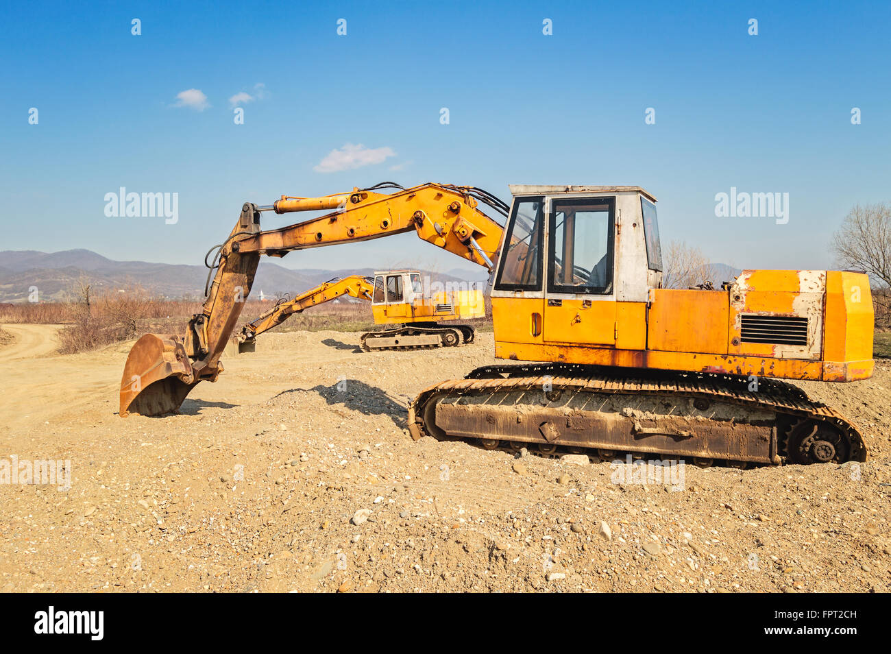 Old and rusty excavators digging out pebbles from the bank of the river ...