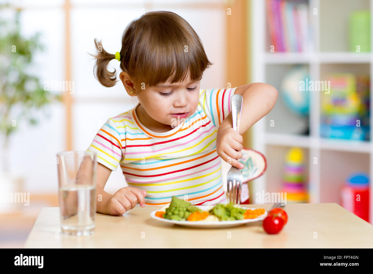 kid girl eating healthy vegetables in kindergarten or nursery Stock ...