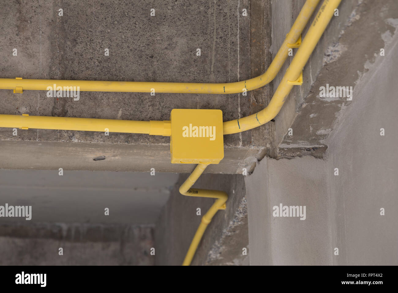 yellow PVC pipes for electrical boxes and wires buried on concrete wall ...