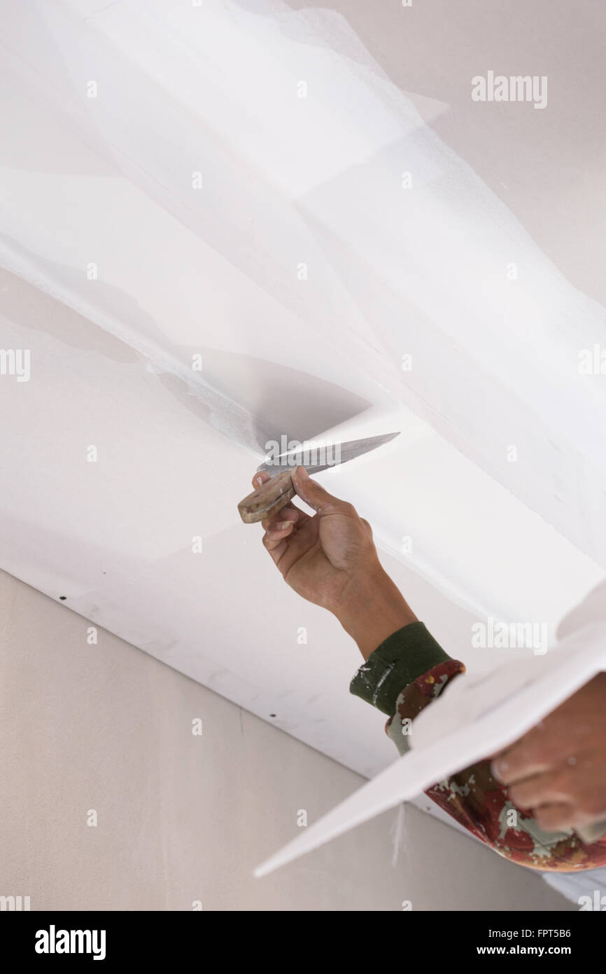 hand of worker using gypsum plaster ceiling joints at construction site ...