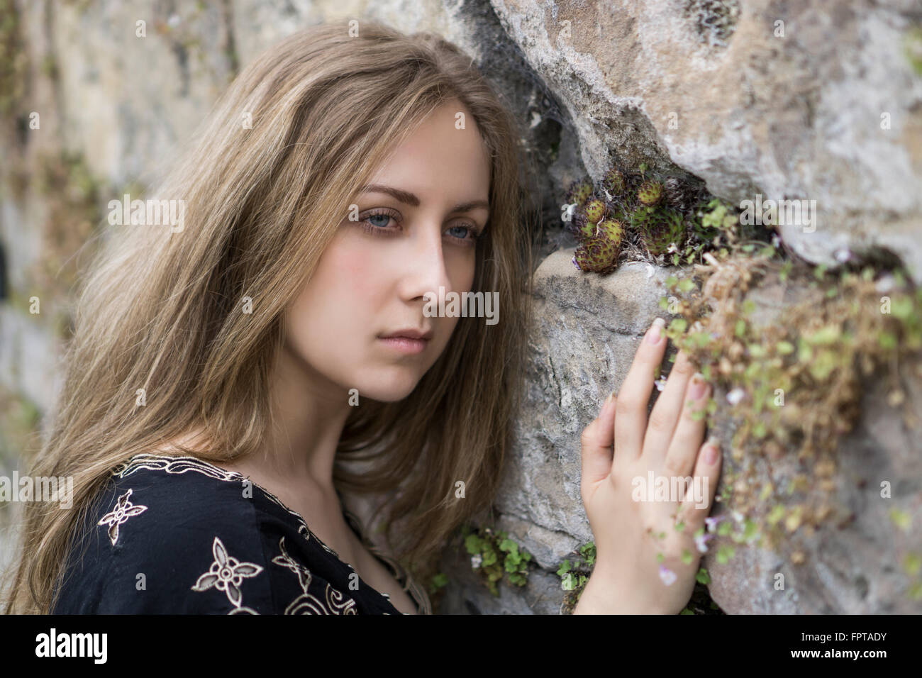 Attractive young woman leaning against the wall looking away with a ...