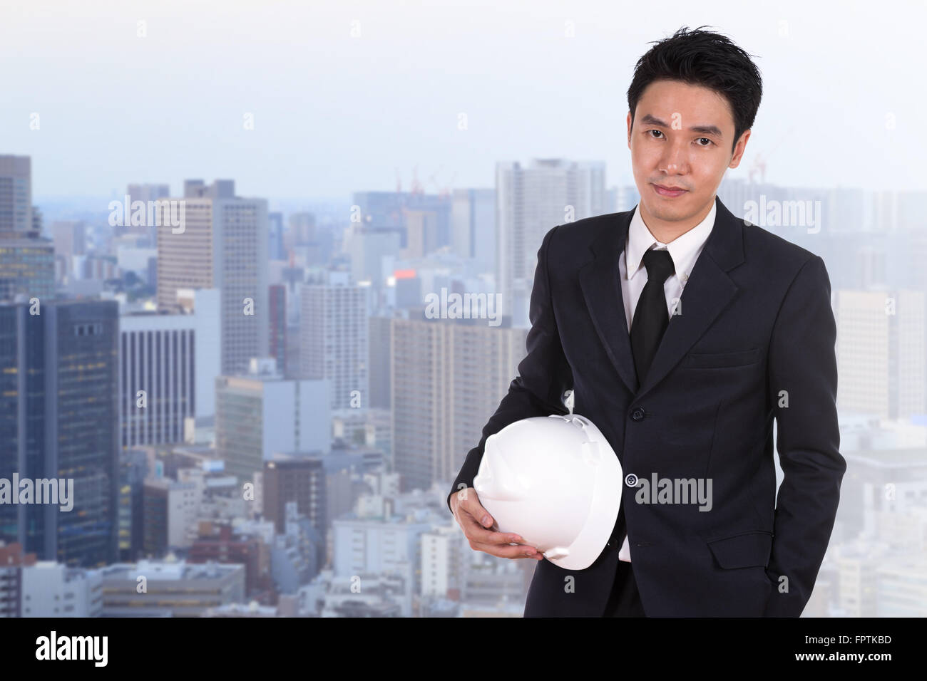 engineer holding white helmet with city background Stock Photo - Alamy