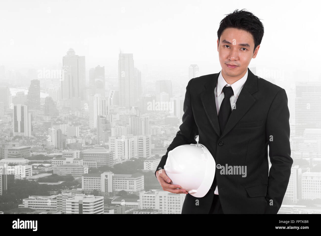 engineer holding white helmet with city background Stock Photo - Alamy