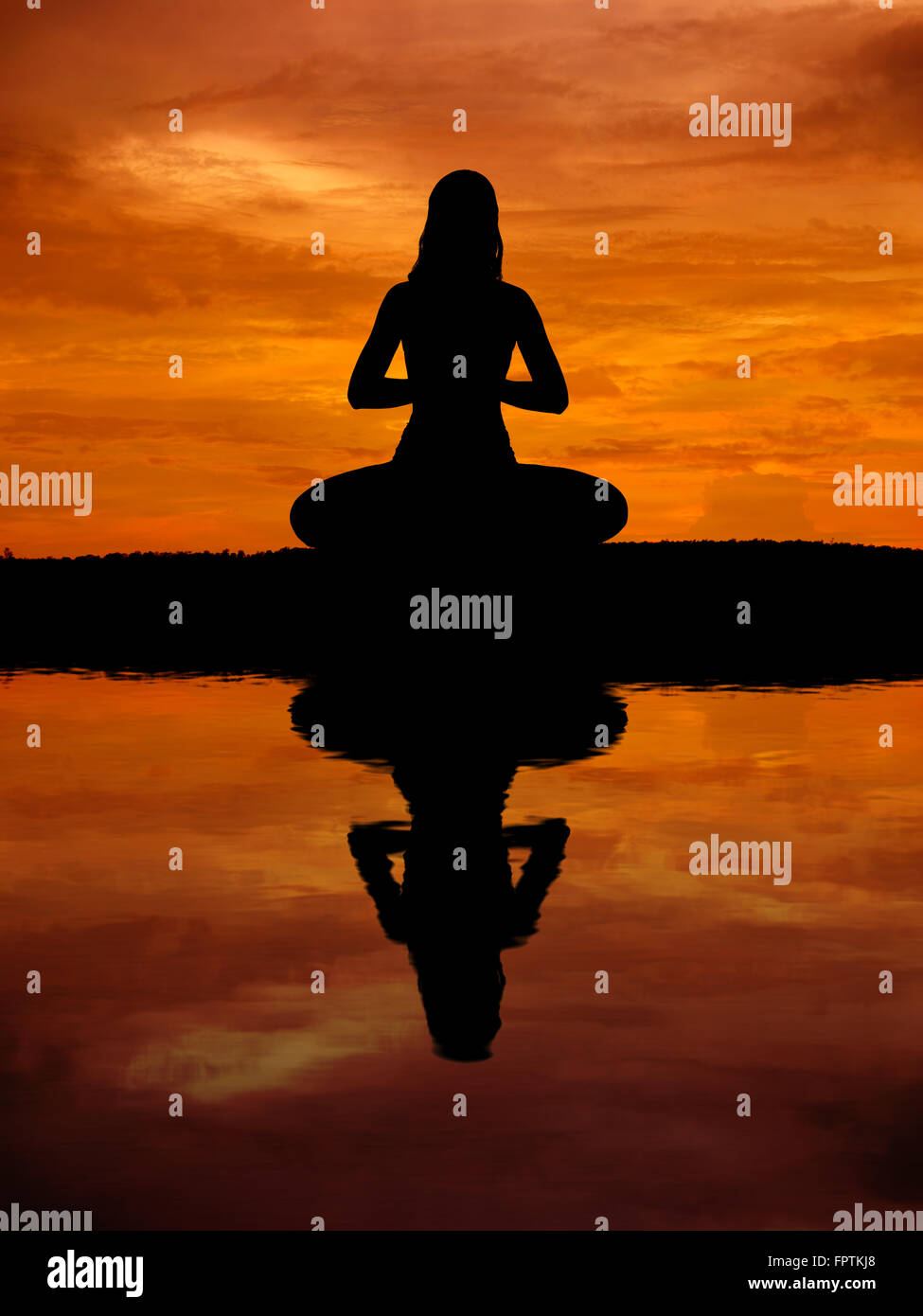 Silhouette of a beautiful Yoga woman with water reflection at sunset ...