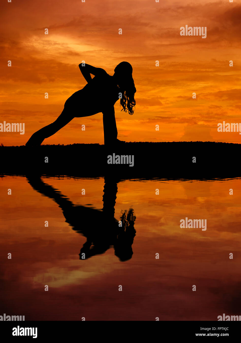Silhouette of a beautiful Yoga woman with water reflection at sunset ...