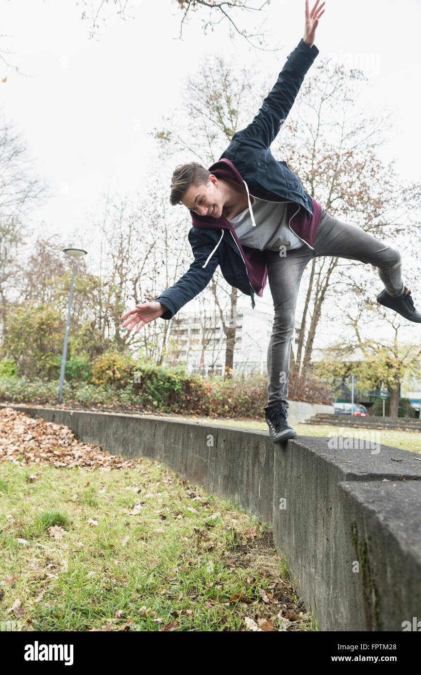 Young man balancing on concrete wall and loosing the balance, Munich ...