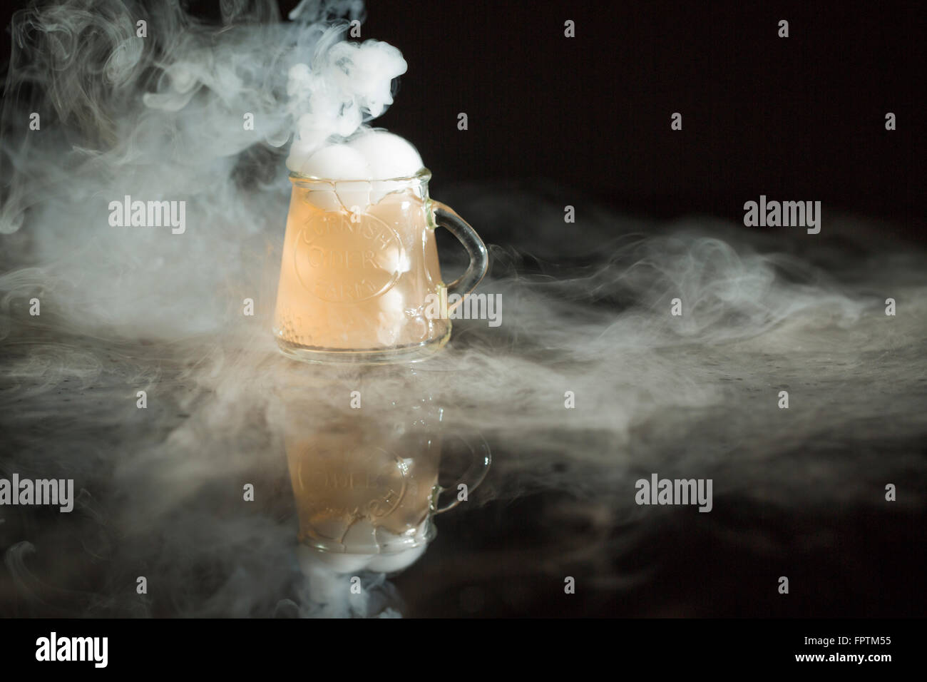 Glass tankard of steaming liquid smoke on black background - potion ...