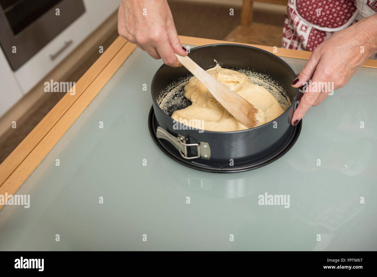 Senior woman filling dough into a spring form pan and making smooth ...