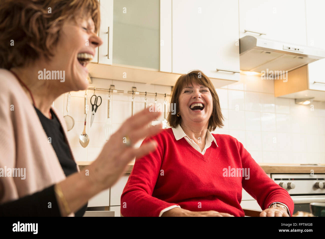 Two senior women talking and laughing in kitchen, Munich, Bavaria ...