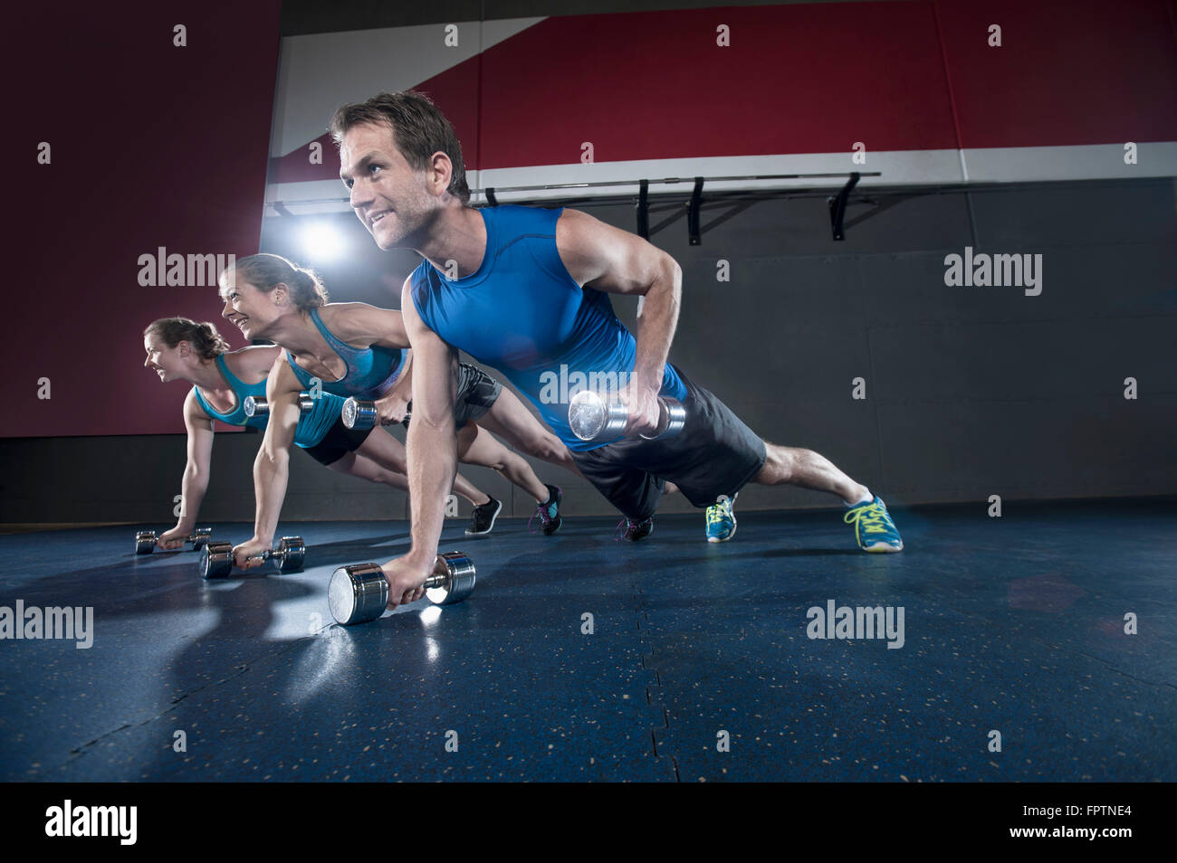 Athletes doing push ups in the gym by holding dumbbell, Bavaria ...