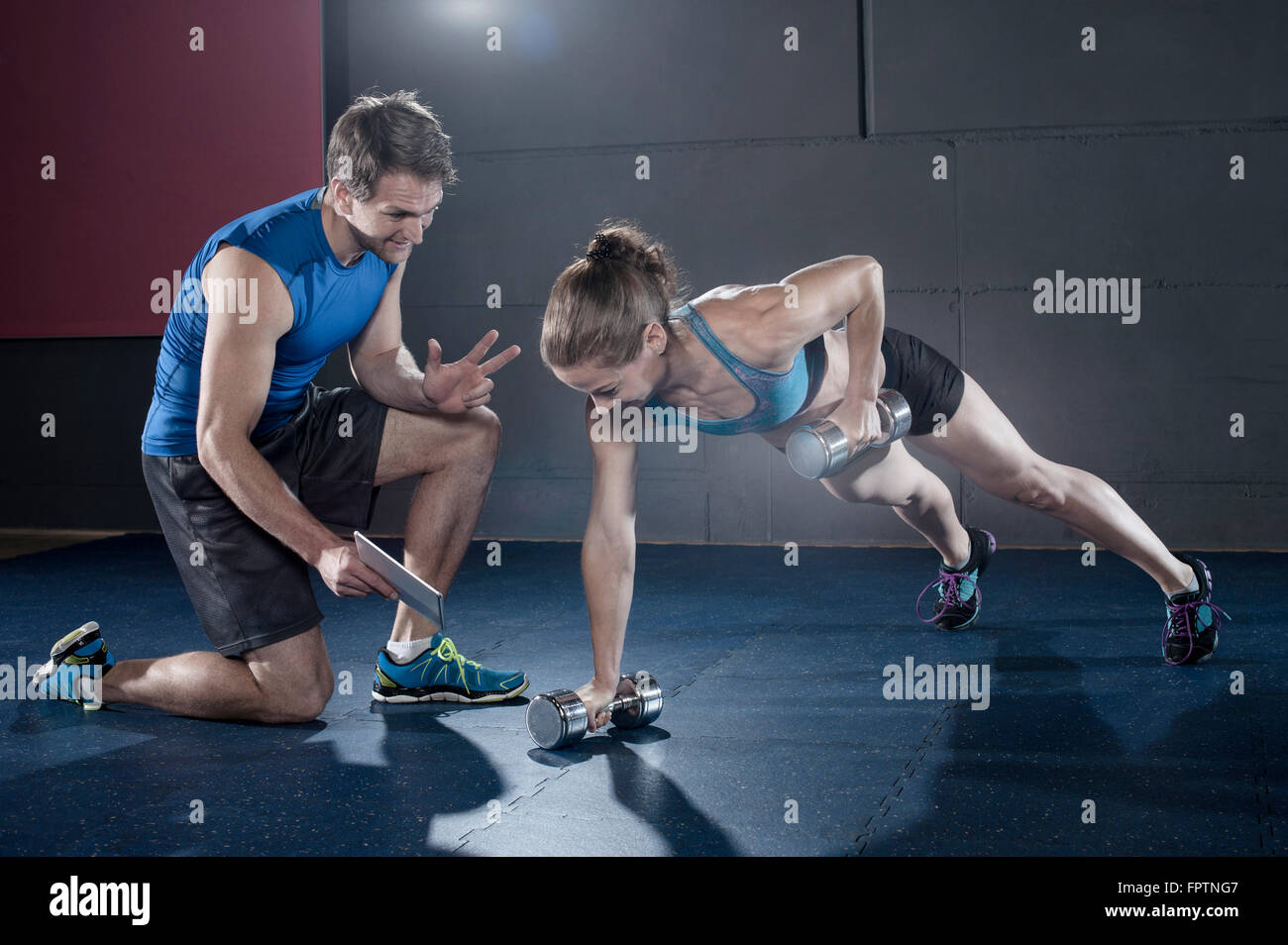 Fitness instructor giving training to client in the gym, Bavaria ...