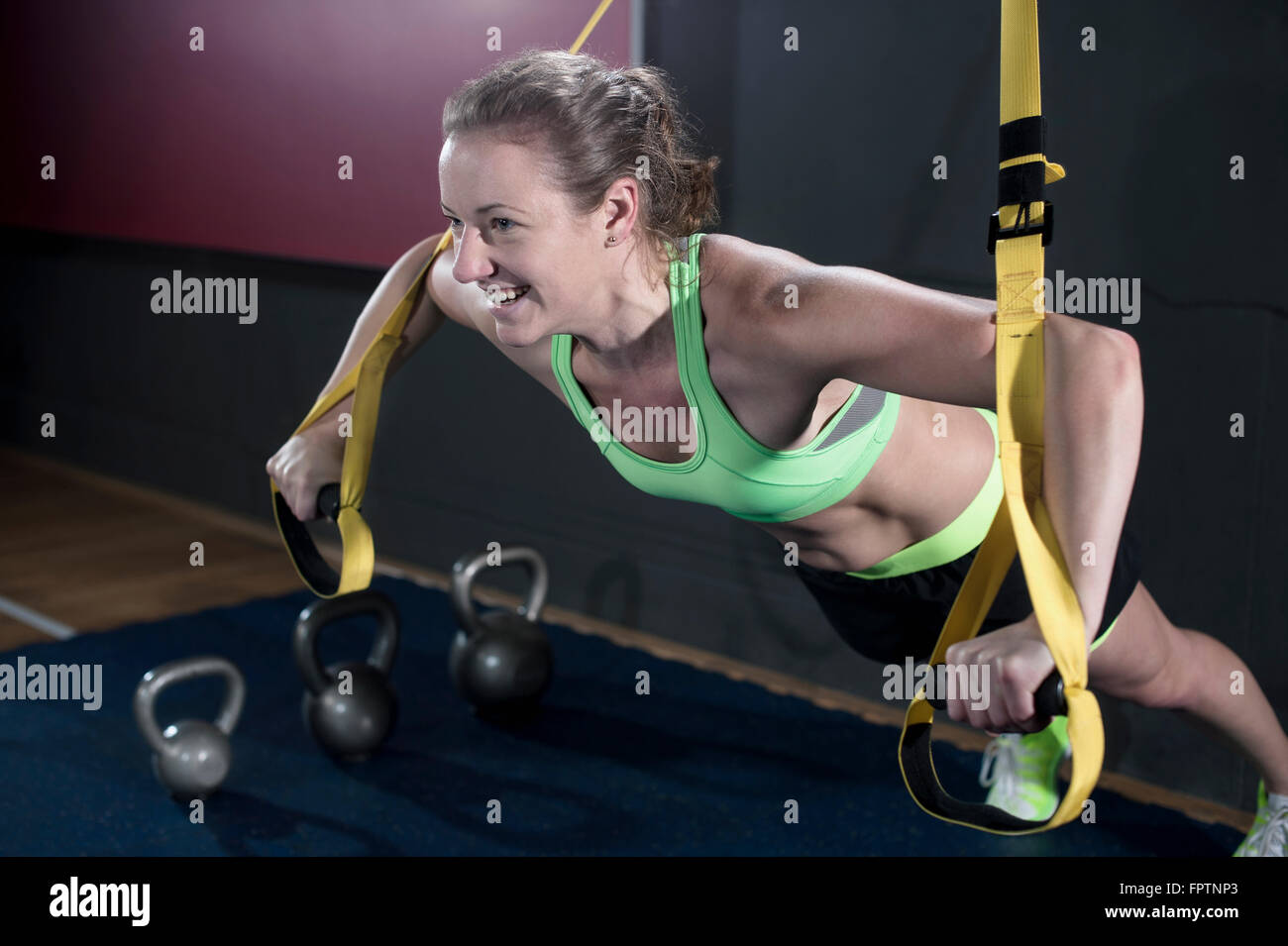 Sportive young woman doing press-ups in the gym with TRX belt, Bavaria ...