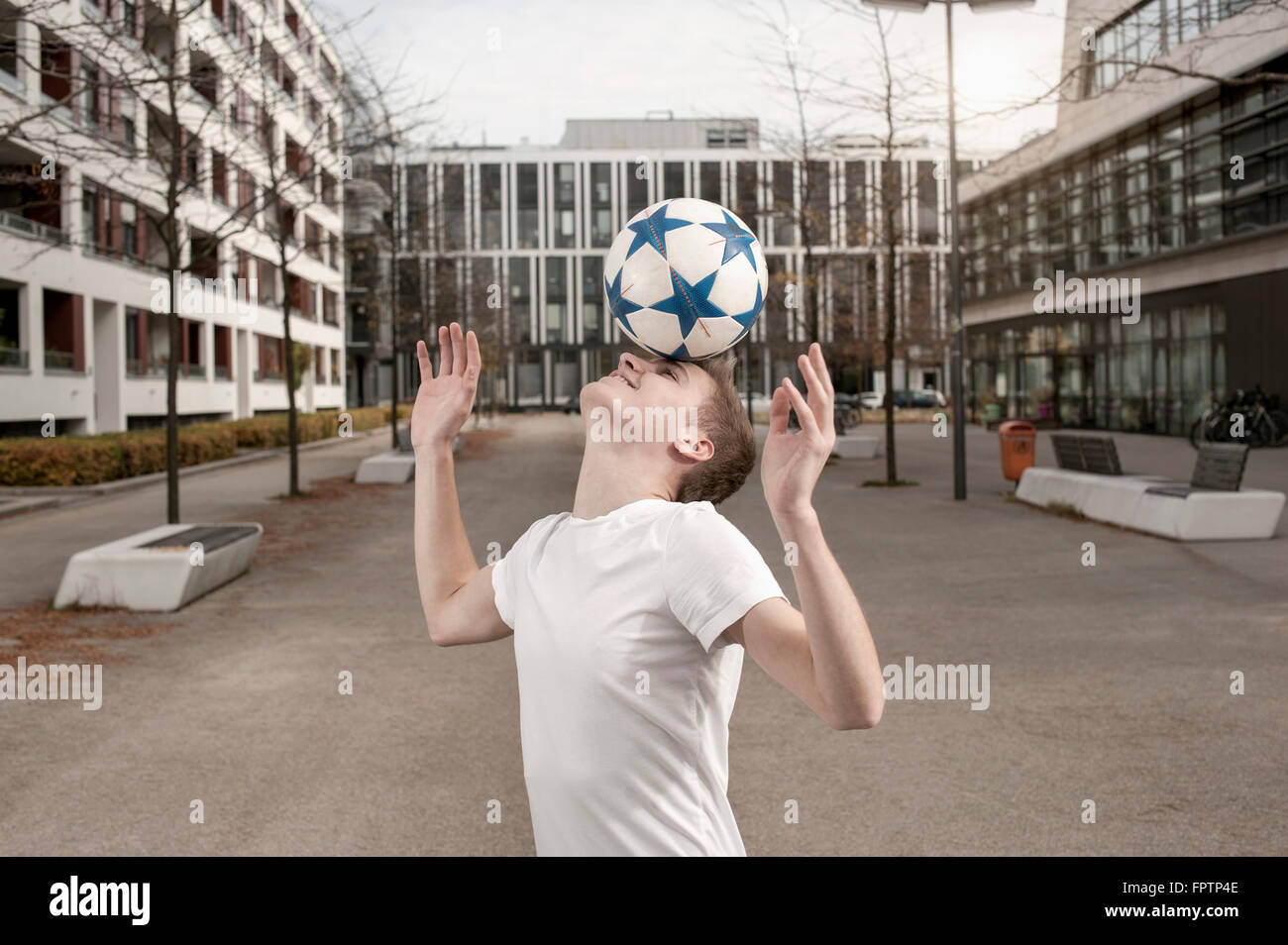 Teenage boy playing football by balancing a ball on his forehead ...