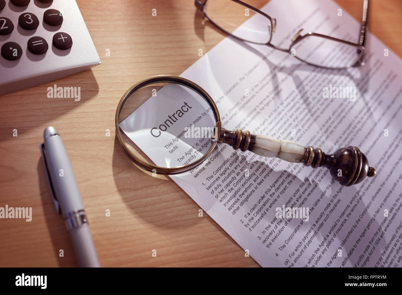 Magnifying glass examining and signing a legal contract document Stock ...
