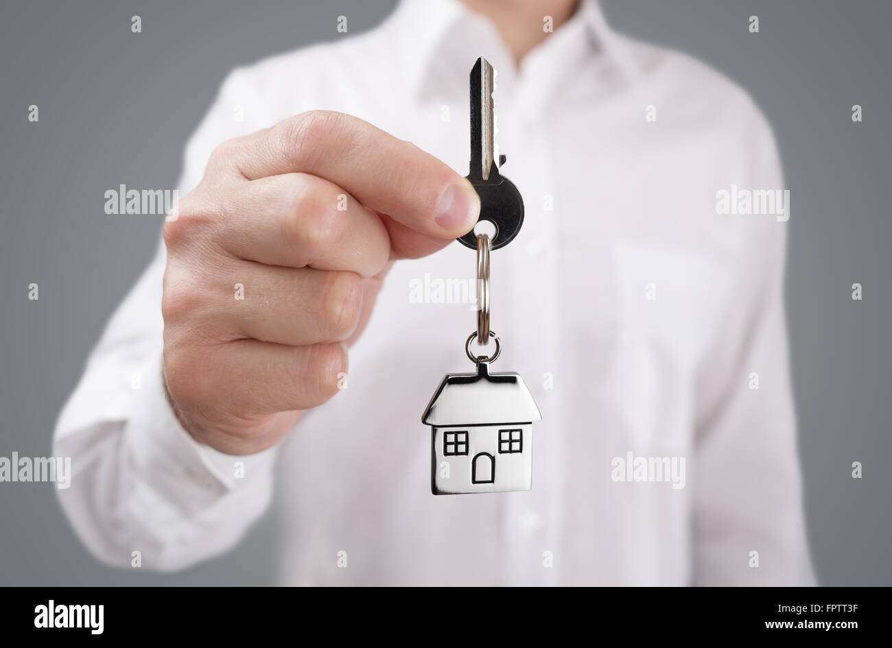 Man holding out house key on a house shaped keychain Stock Photo - Alamy