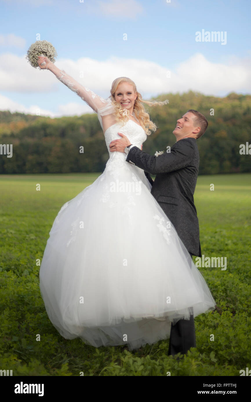 Groom lifting up bride in field, Ammersee, Upper Bavaria, Bavaria ...