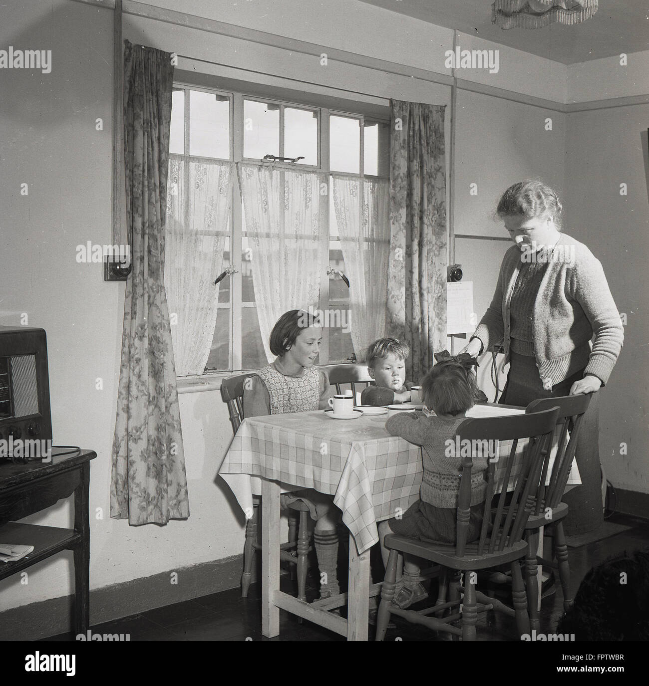 1950s historical picture of a front room, mother serves tea to her ...
