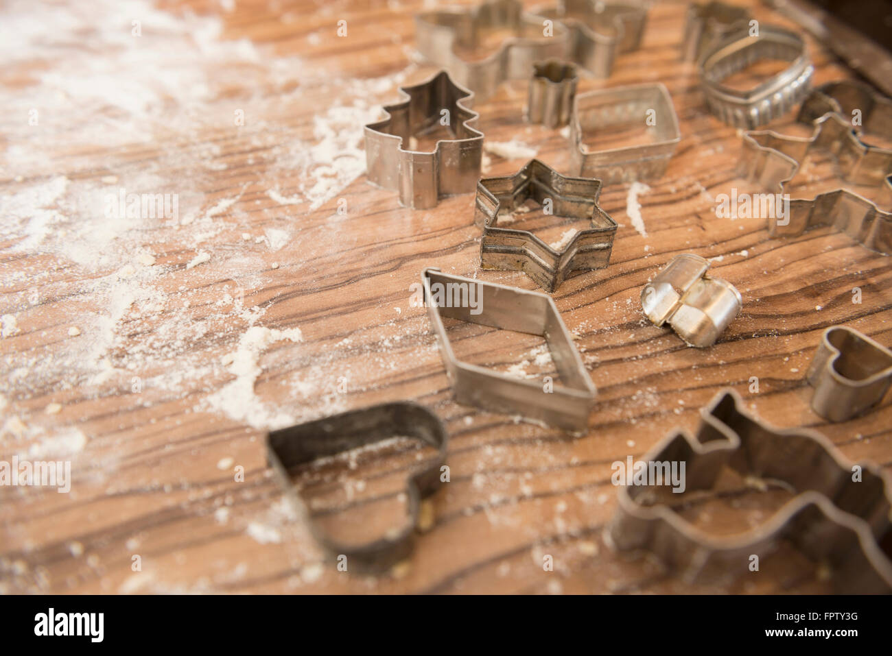 Variety of different cookie cutters and scattered flour on dark wood ...