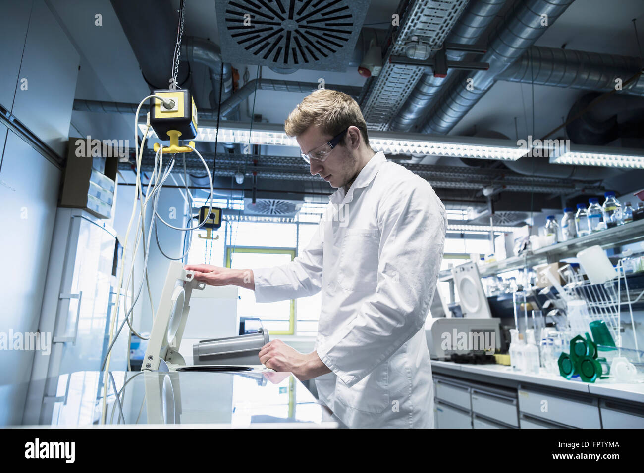 Side view of a male scientific researcher using microscope in the ...
