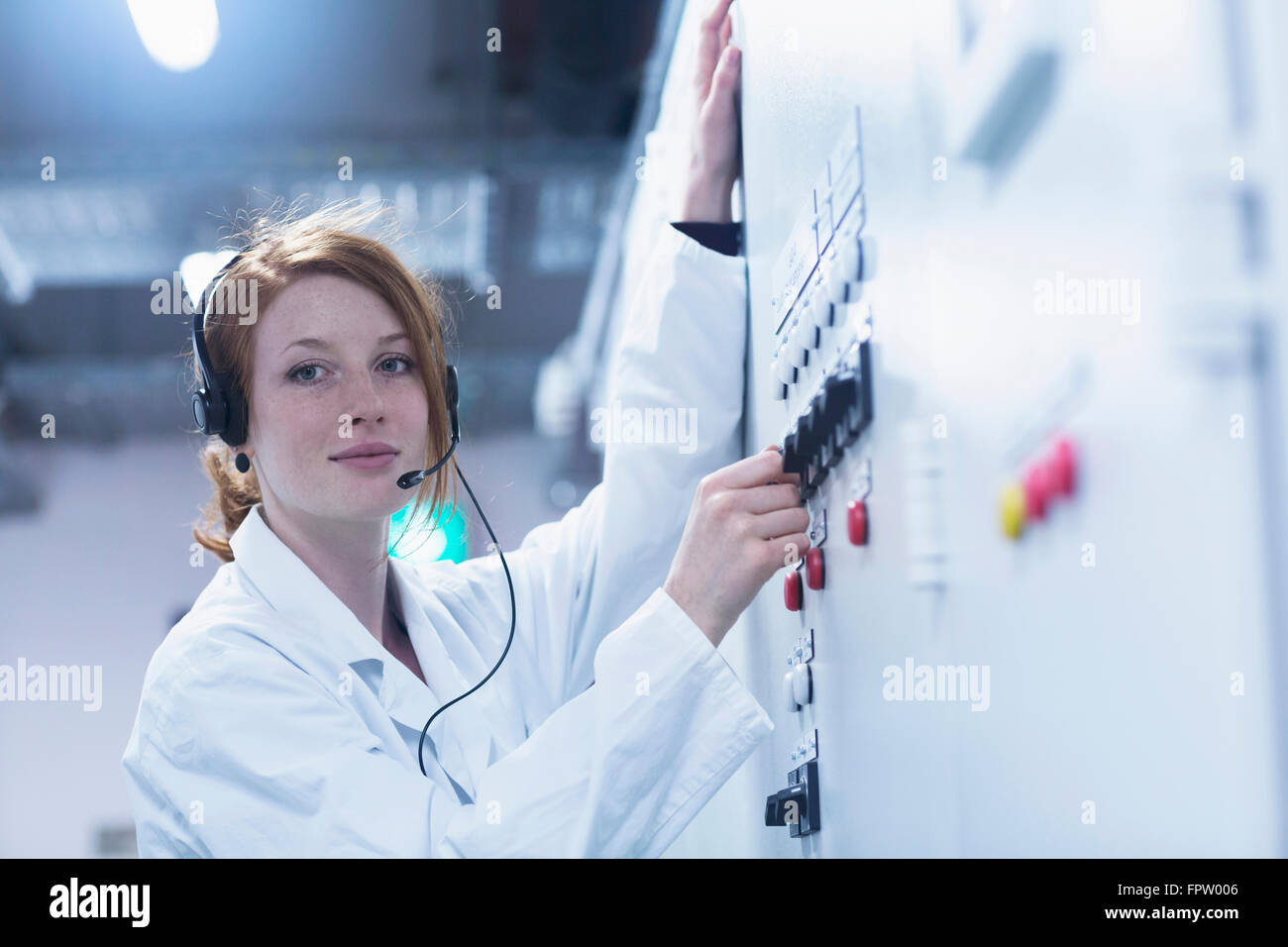 Young female engineer wearing headset and controlling a switch gear in ...