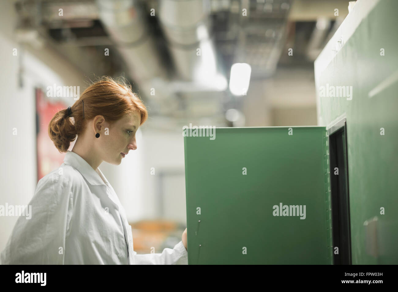 Young female engineer controlling a switch gear in control room ...