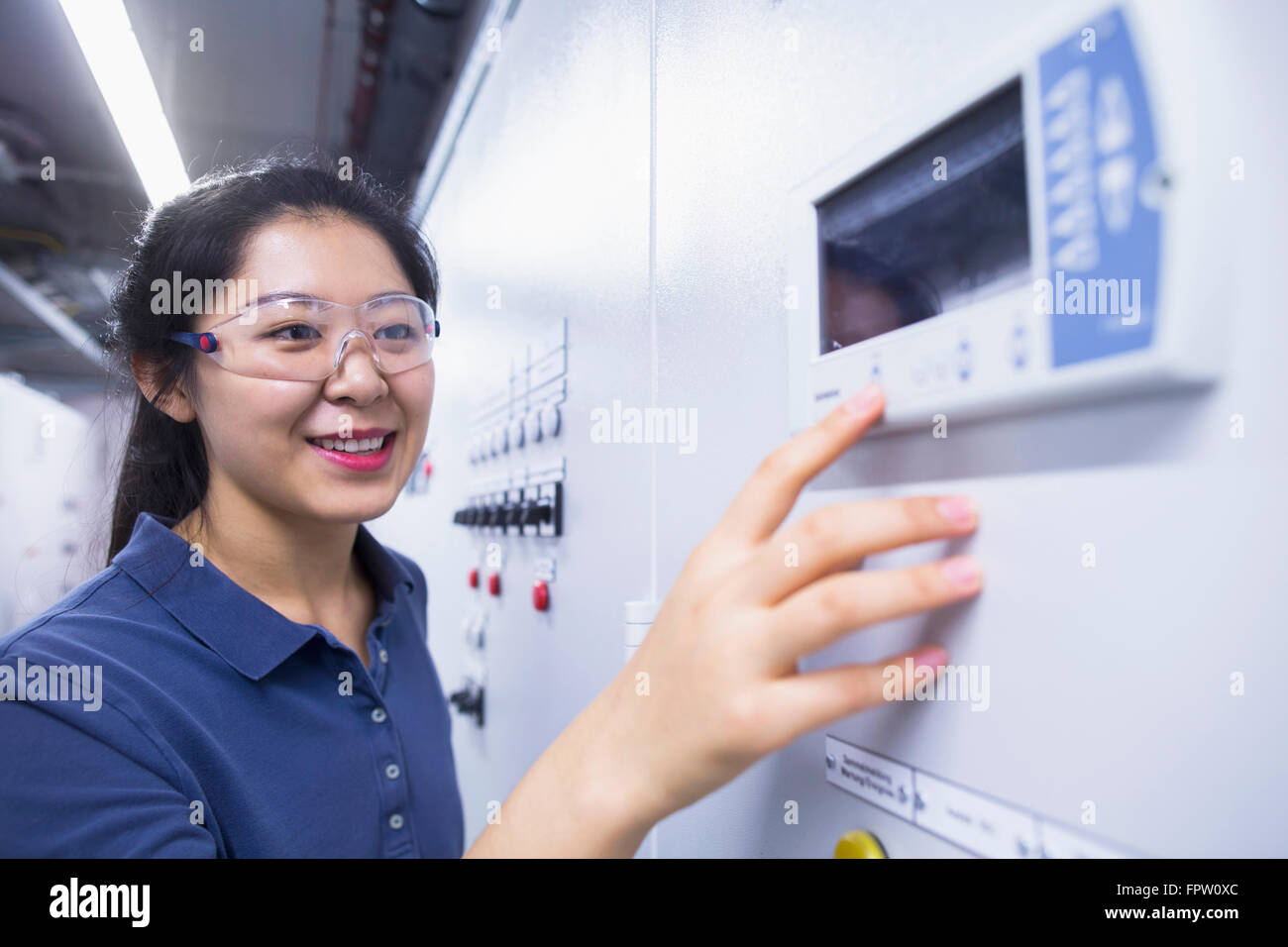 Young female engineer working at control panel in an industrial plant, Freiburg Im Breisgau ...