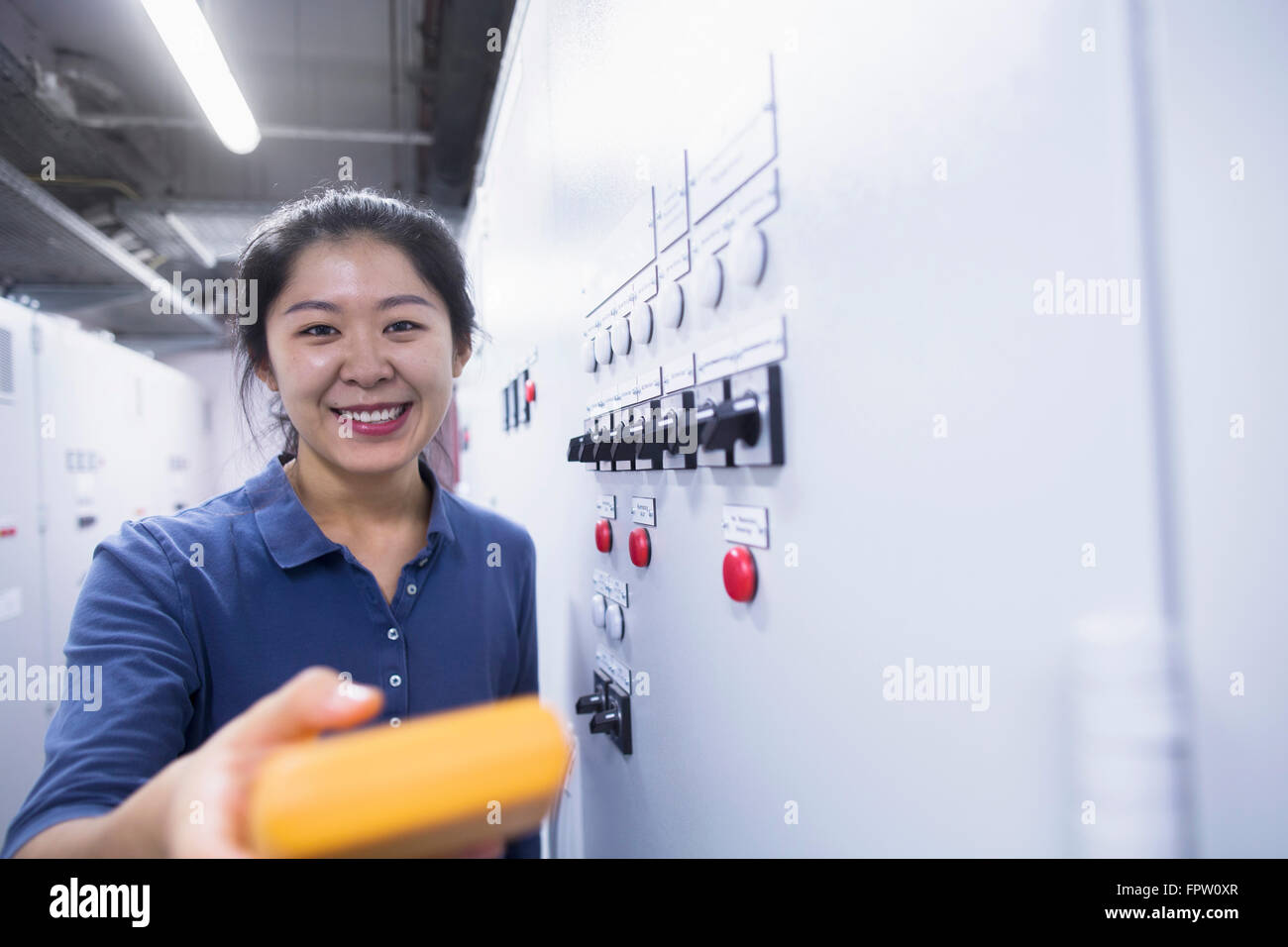 Young female engineer examining control panel with multimeter in an ...