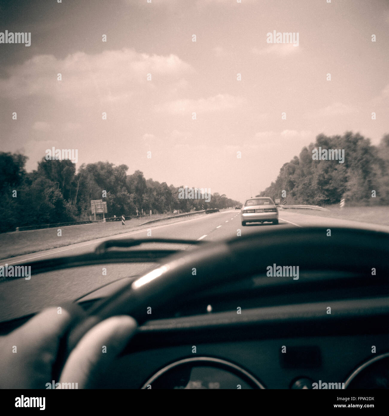 DRIVER VIEW OF HIGHWAY OVER AUTOMOBILE DASHBOARD HAND ON STEERING WHEEL ...