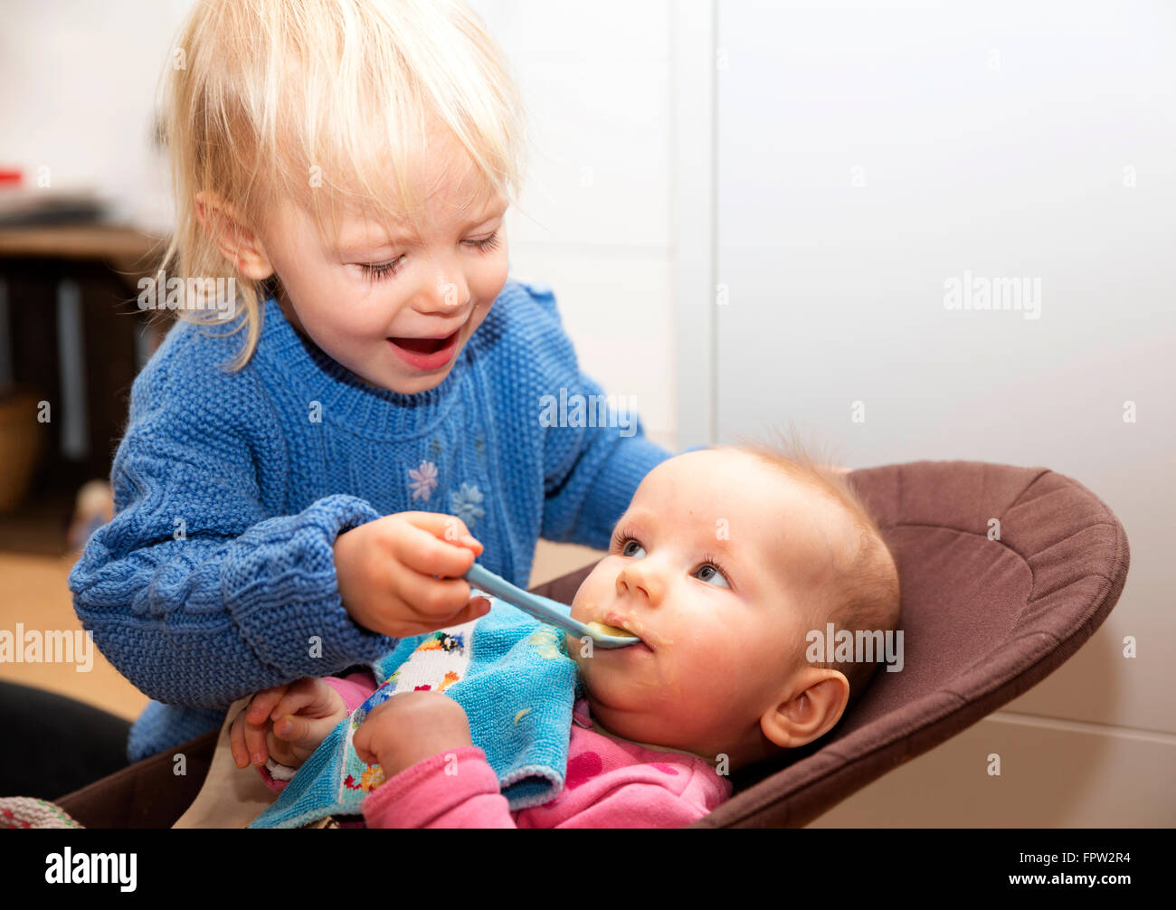 Siblings sister spoon feeding baby brother hi-res stock photography and ...