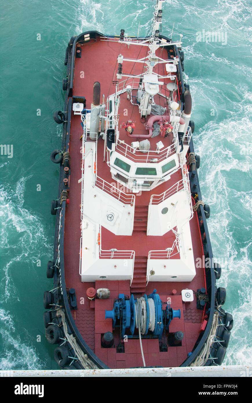 Tug boat pushing large ship and moving it into port Stock Photo - Alamy