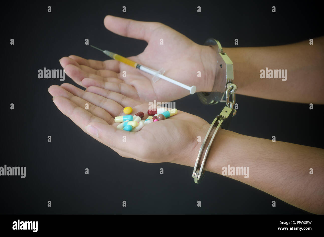 syringe and drug in hand and handcuffs Stock Photo - Alamy