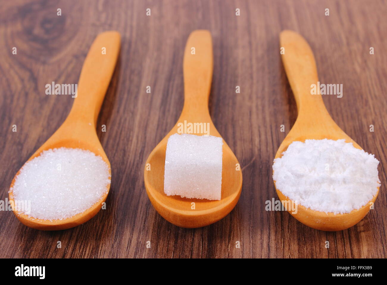 Sugar cube, granulated and powdered sugar on wooden spoons, ingredient ...