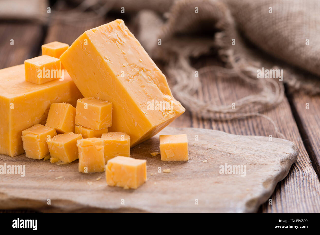 Pieces of Cheddar (close-up shot) on an old wooden table Stock Photo ...