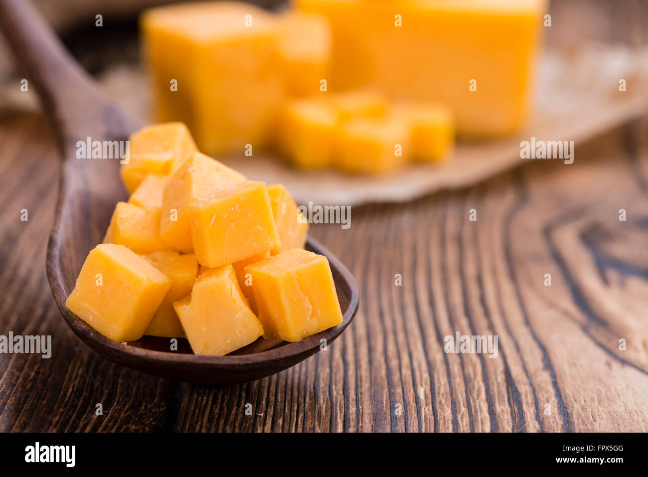 Pieces of Cheddar (close-up shot) on an old wooden table Stock Photo ...