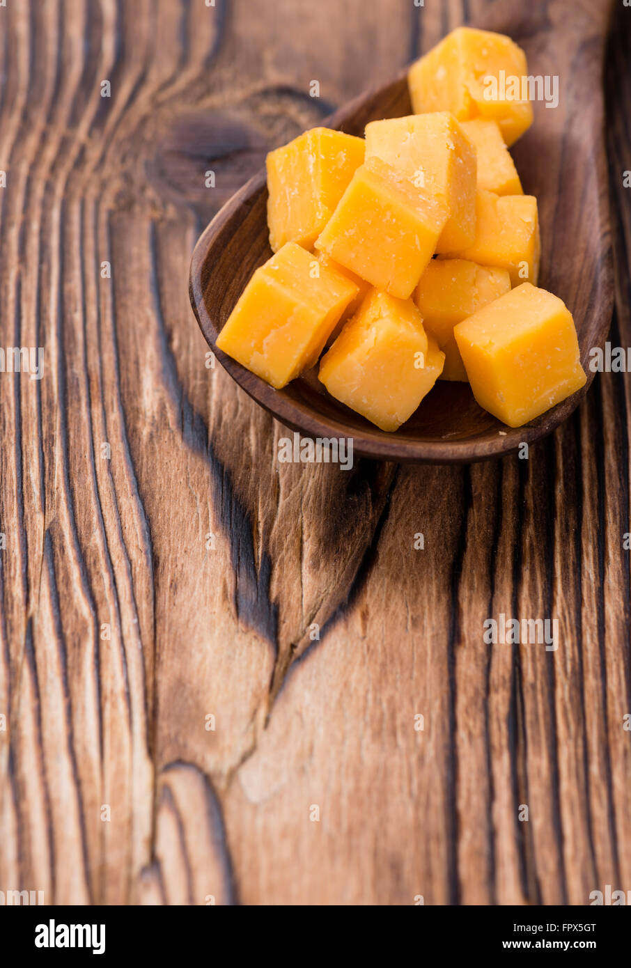 Portion of Cheddar (detailed close-up shot) on vintage wooden ...