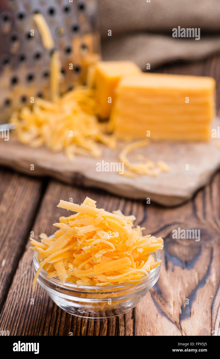 Heap of grated Cheddar Cheese (close-up shot) in rustic background ...