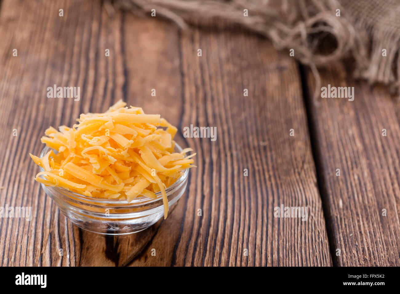 Cheddar Cheese (grated) as close-up shot on an old vintage wooden table ...