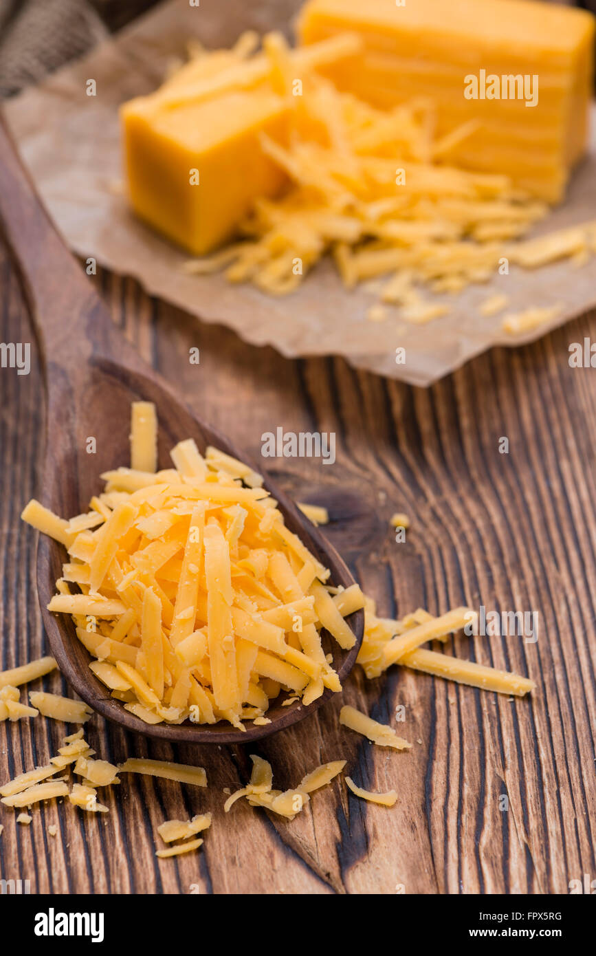 Heap of grated Cheddar Cheese (close-up shot) in rustic background ...